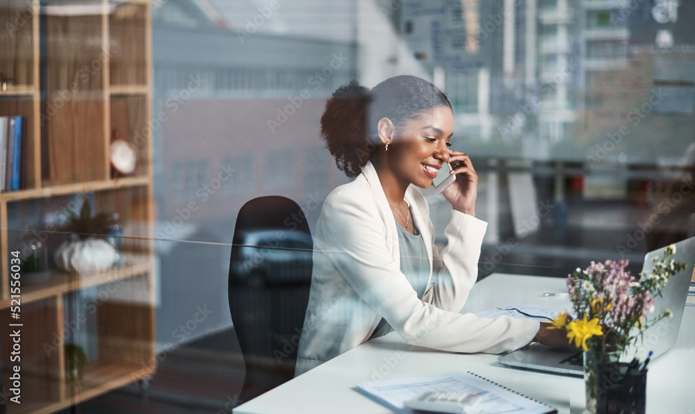 Business woman on a phone call sitting at a desk typing an email on a ...