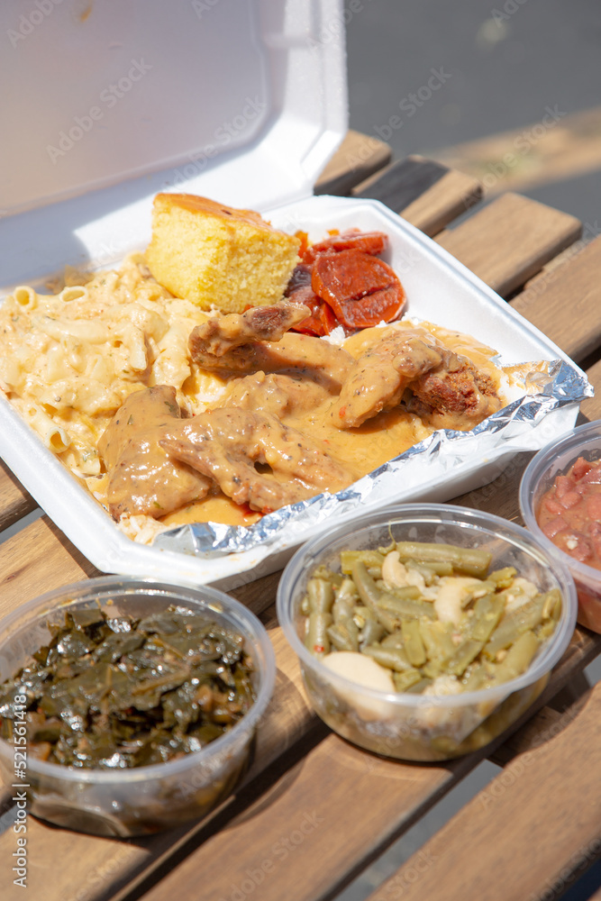 A view of a styrofoam container of soul food, featuring smothered ...