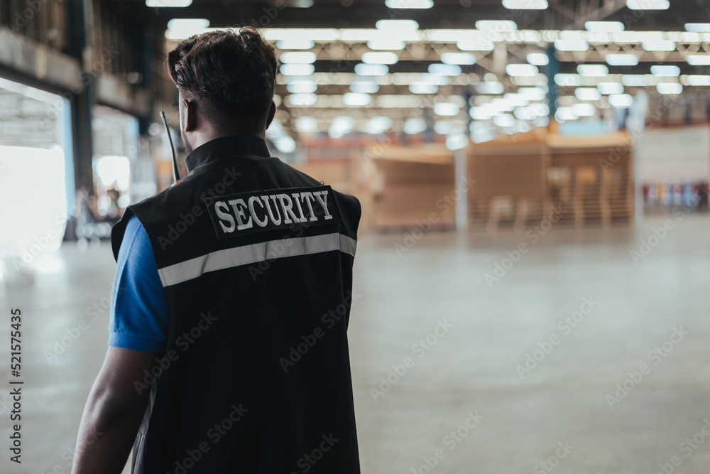Security guard using portable radio transmitter in warehouse. Officer ...
