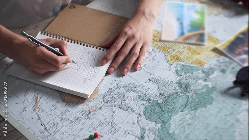 A table with a map on it. A woman makes a travel itinerary. Traveler ...