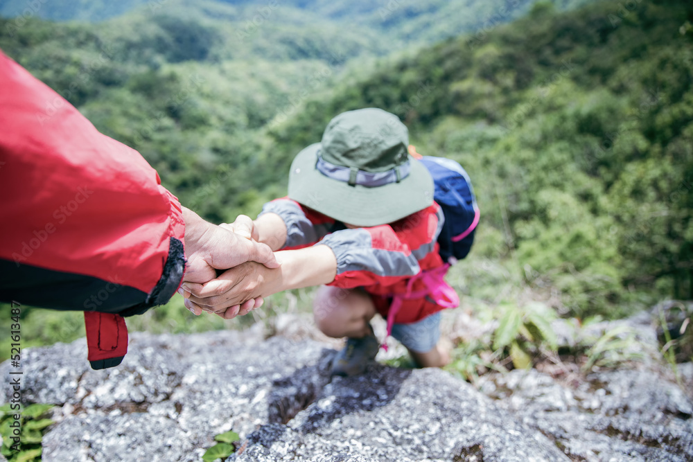 Person hike friends helping each other up a mountain. Man and woman ...