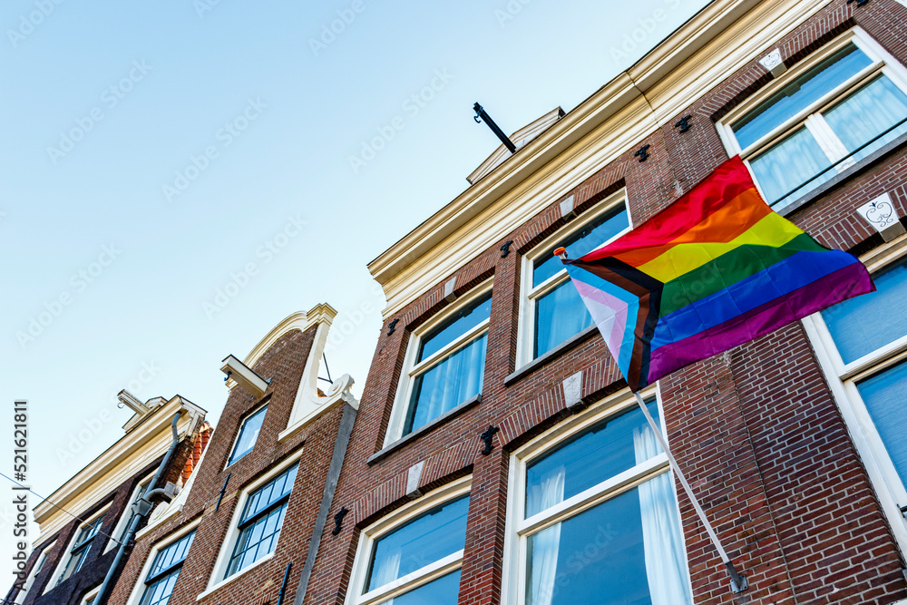 Old Dutch canal houses in Amsterdam with a Progress Pride Flag on their ...