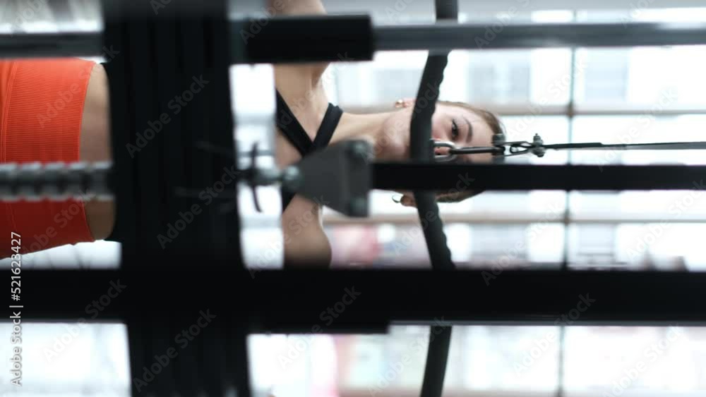 Vertical video, woman trains the back muscles in the gym, she pumps the ...