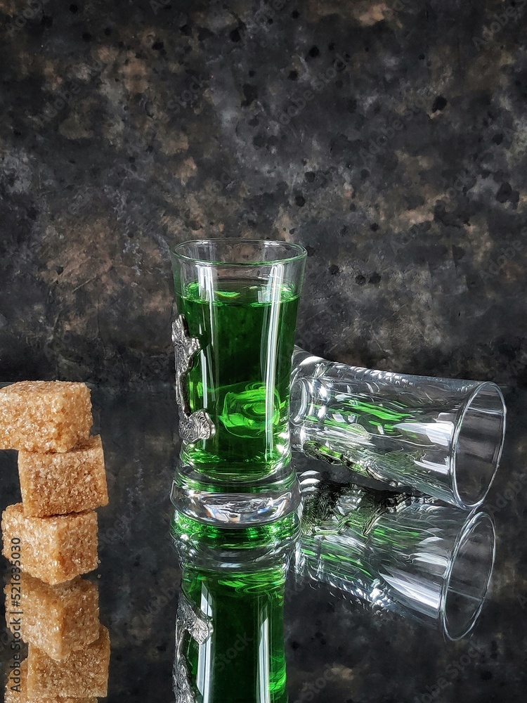 Shot with absinthe on black concrete background. Green alcohol drink ...