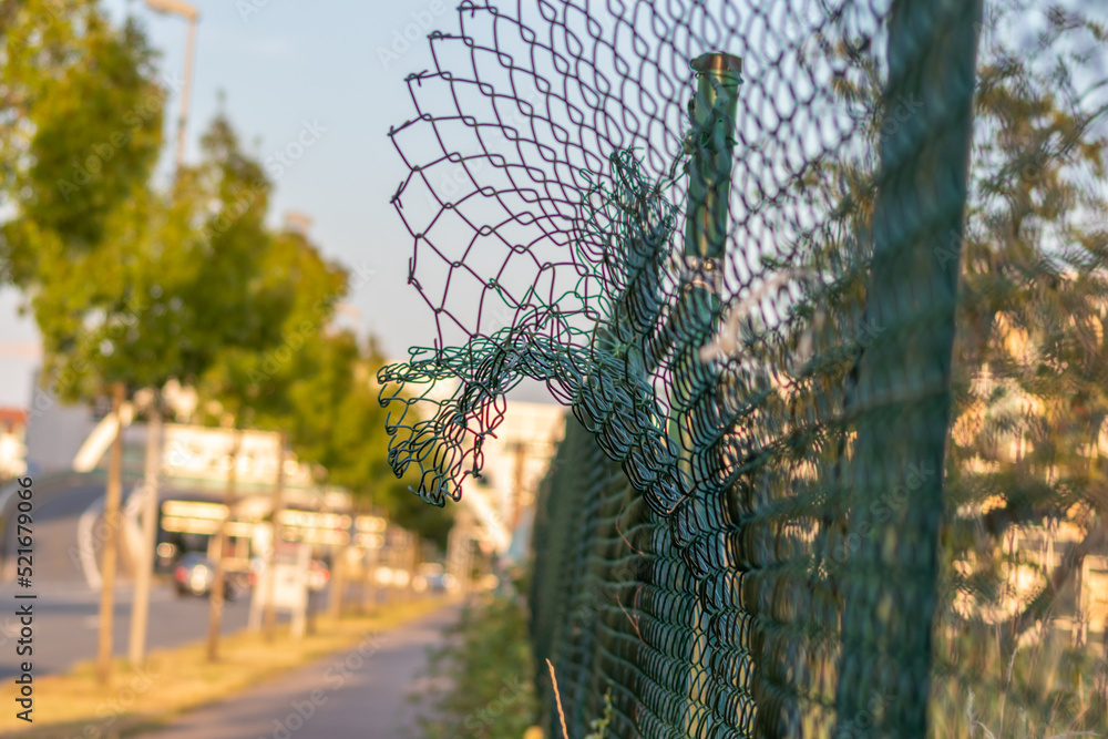 Green damaged wire-mesh fence is ruined after collision with car ...