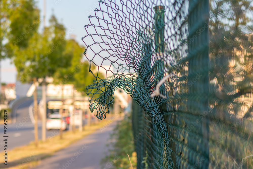 Green damaged wire-mesh fence is ruined after collision with car ...