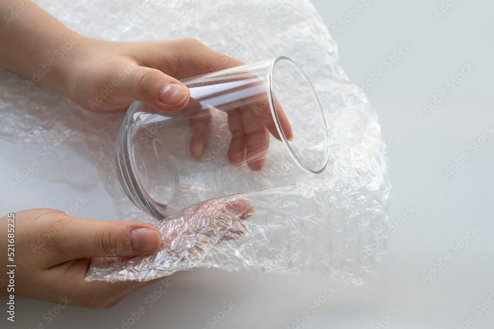Woman hands packaging a glass for water with white transparent bubble ...