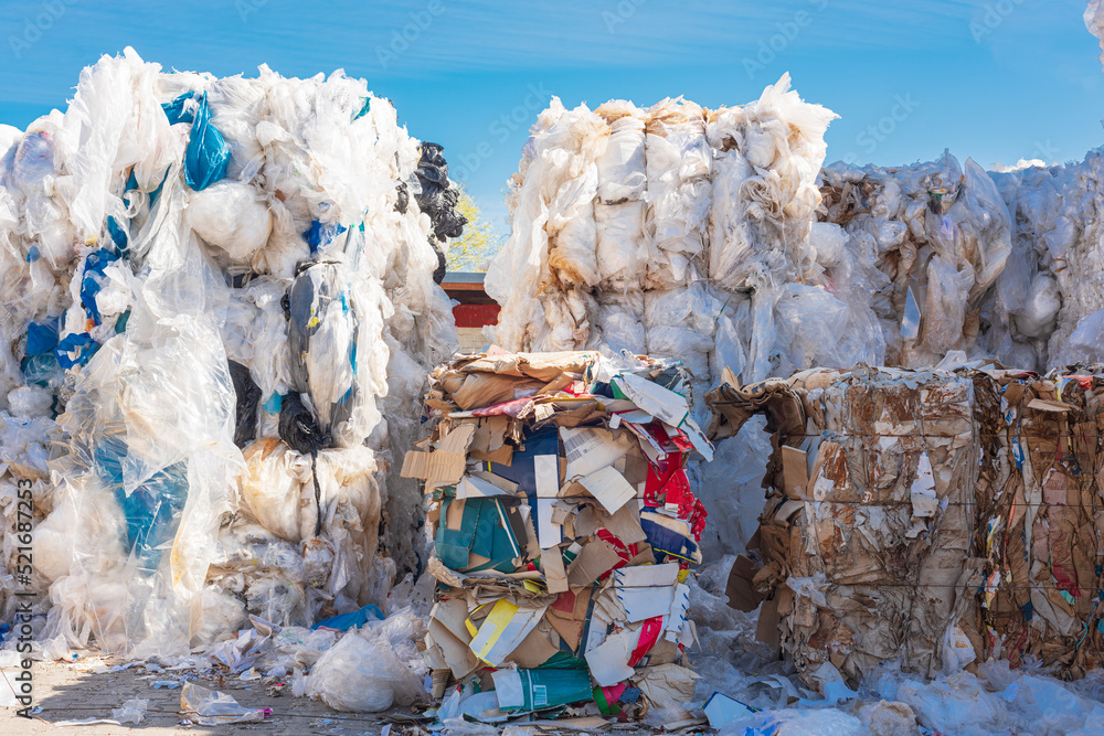 stacks of old waste paper and plastic waste in front of recycling ...