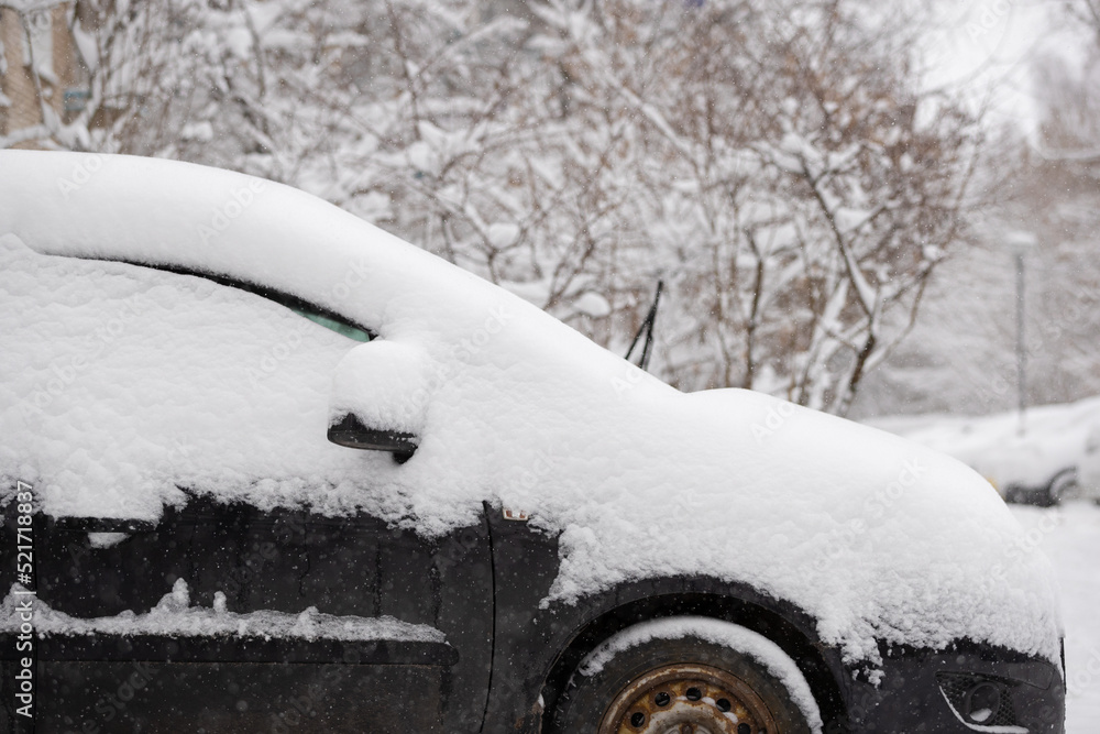 Heavy snowfall covered roads and cars. The car in the parking lot is ...
