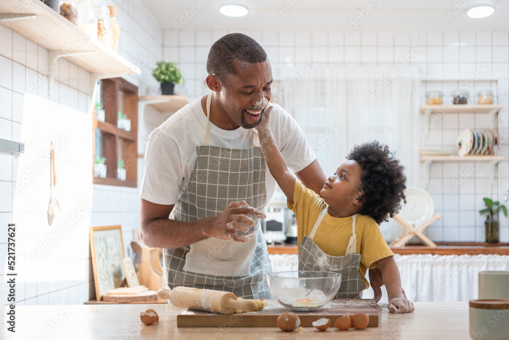 Happy smiling Black son touching his father face with flour while doing ...