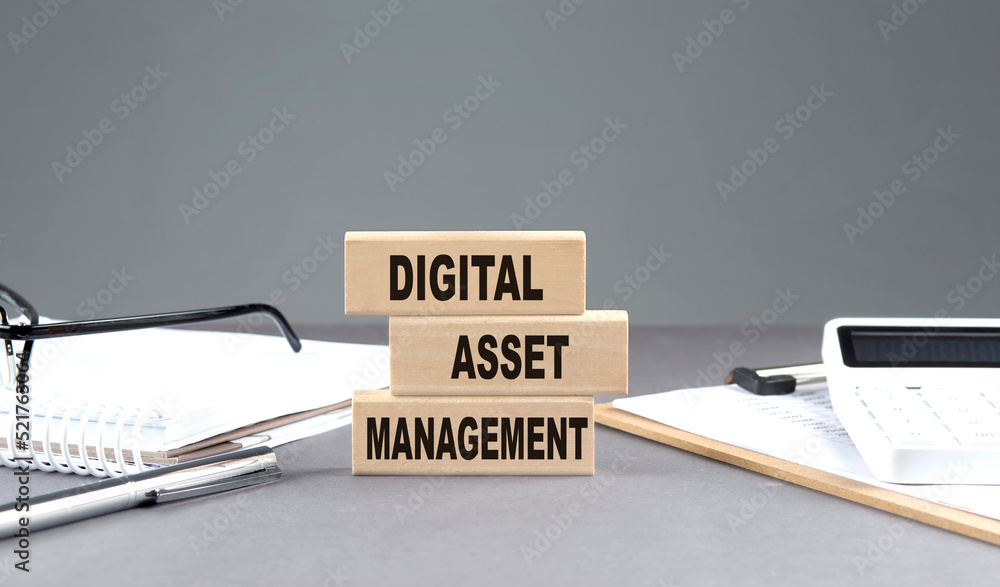 DIGITAL ASSET MANAGEMENT text on wooden block with notebook,chart and ...