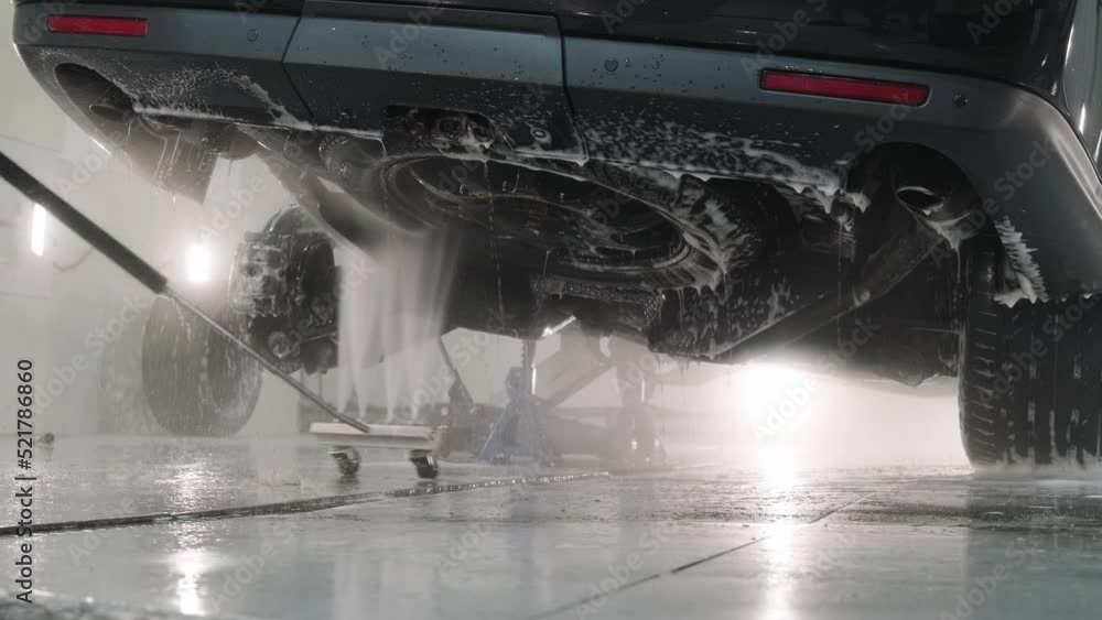 Washing the bottom of the car with water after foam washing in the car ...