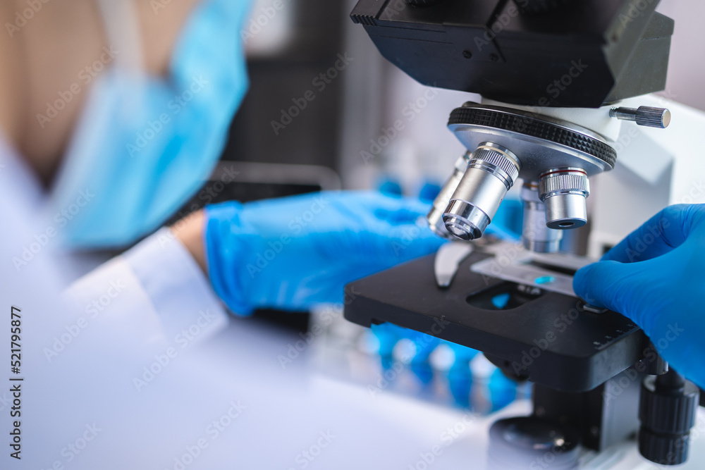 Scientist analyzing microscope slide at laboratory. Young woman ...
