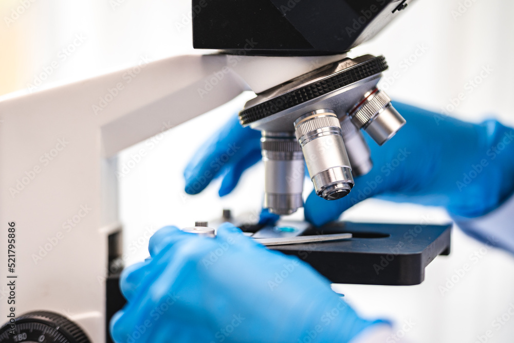 Scientist analyzing microscope slide at laboratory. Young woman ...