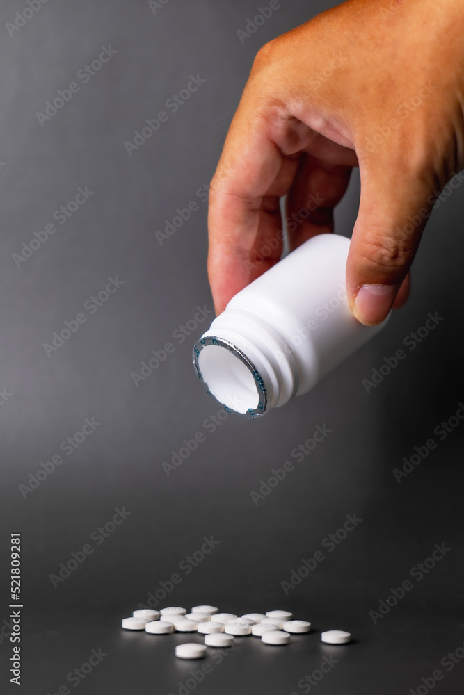 Hand holding unlabeled white plastic pill bottle open cap Poured out ...