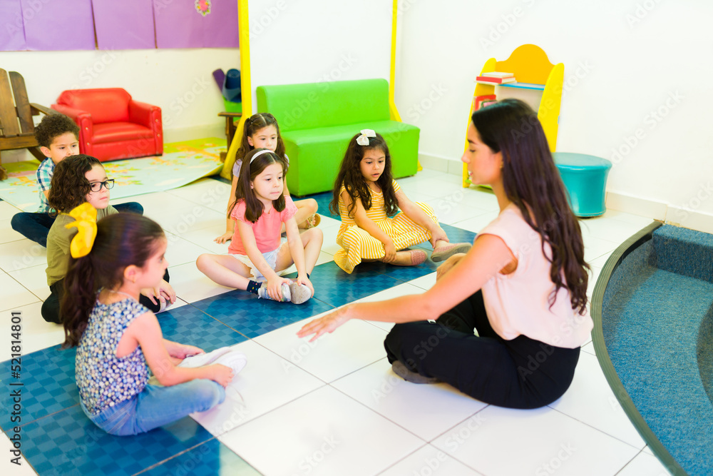 Relaxed teacher teaching breathing exercises to little students Stock ...
