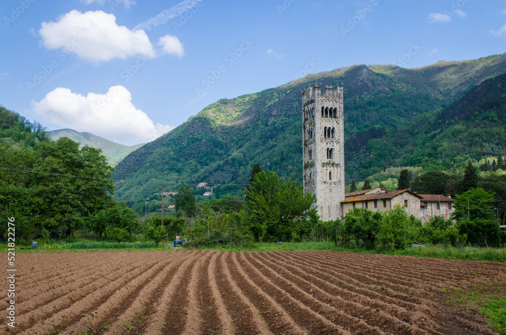 Il campanile di una chiesa e un campo arato nella camagna della valle ...