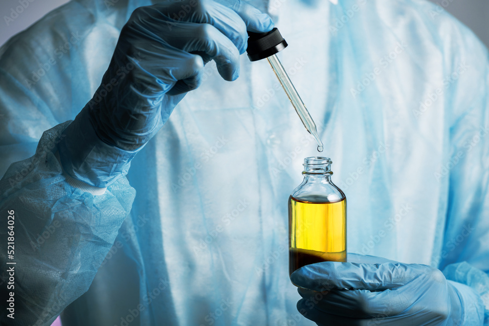 Gloved doctor hands with pipette dropping liquid substance into ...