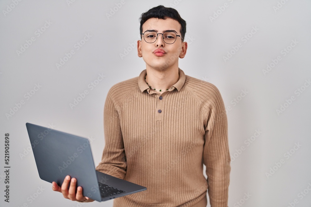 Non binary person using computer laptop looking at the camera blowing a ...