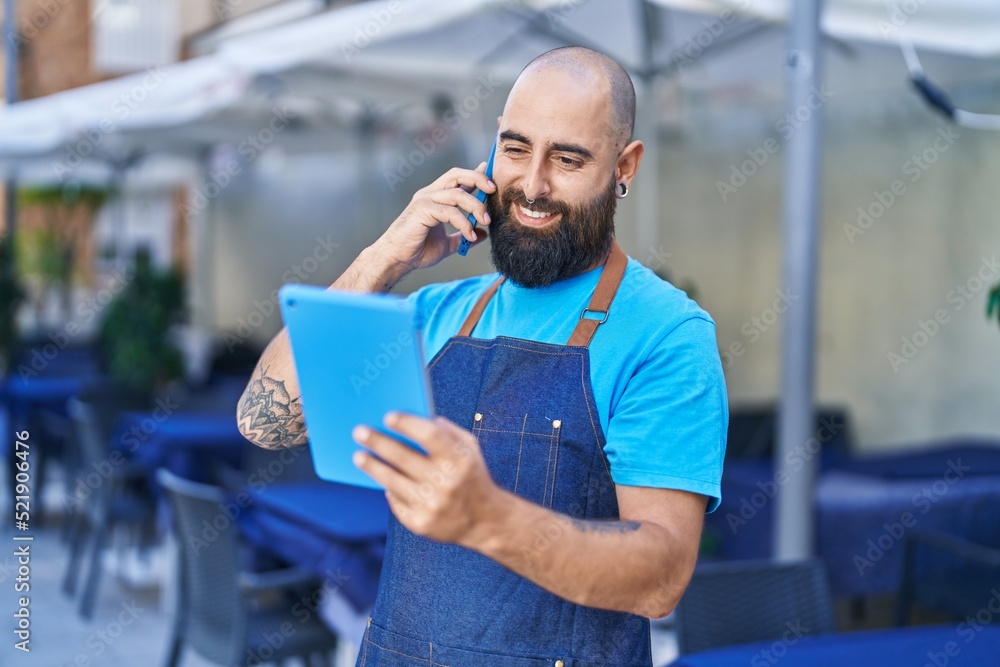Young bald man waitress touchpad smartphone at coffee shop terrace ...