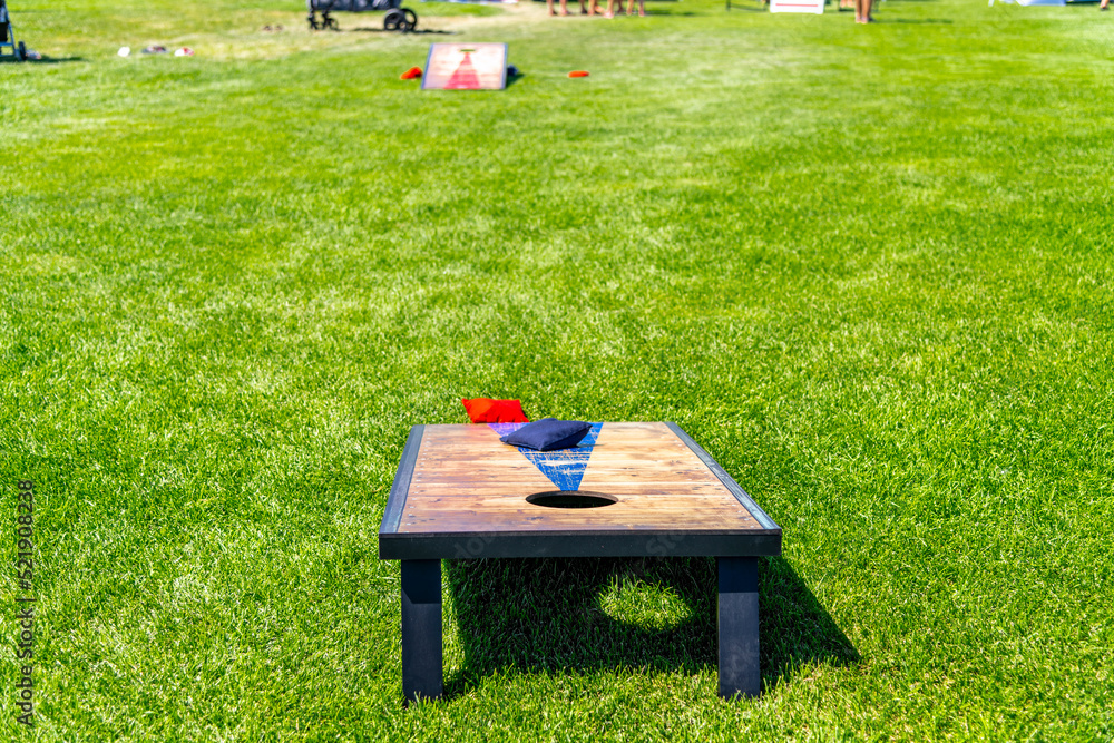 Two cornhole boards on a green lawn. Cornhole is a game popular in ...