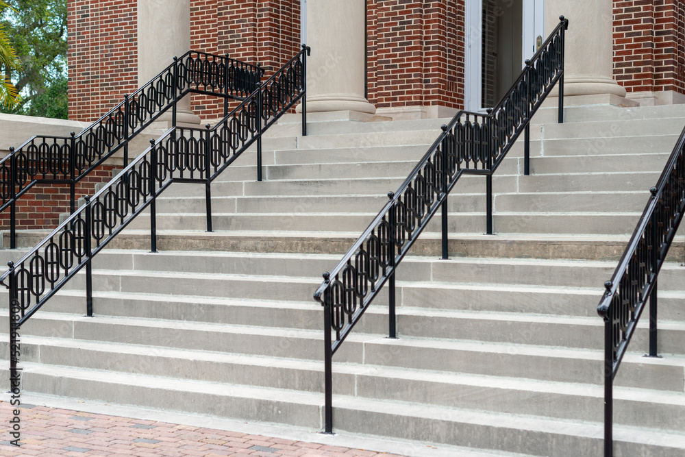 Concrete steps lead to multiple doors of a historic building. The walls ...