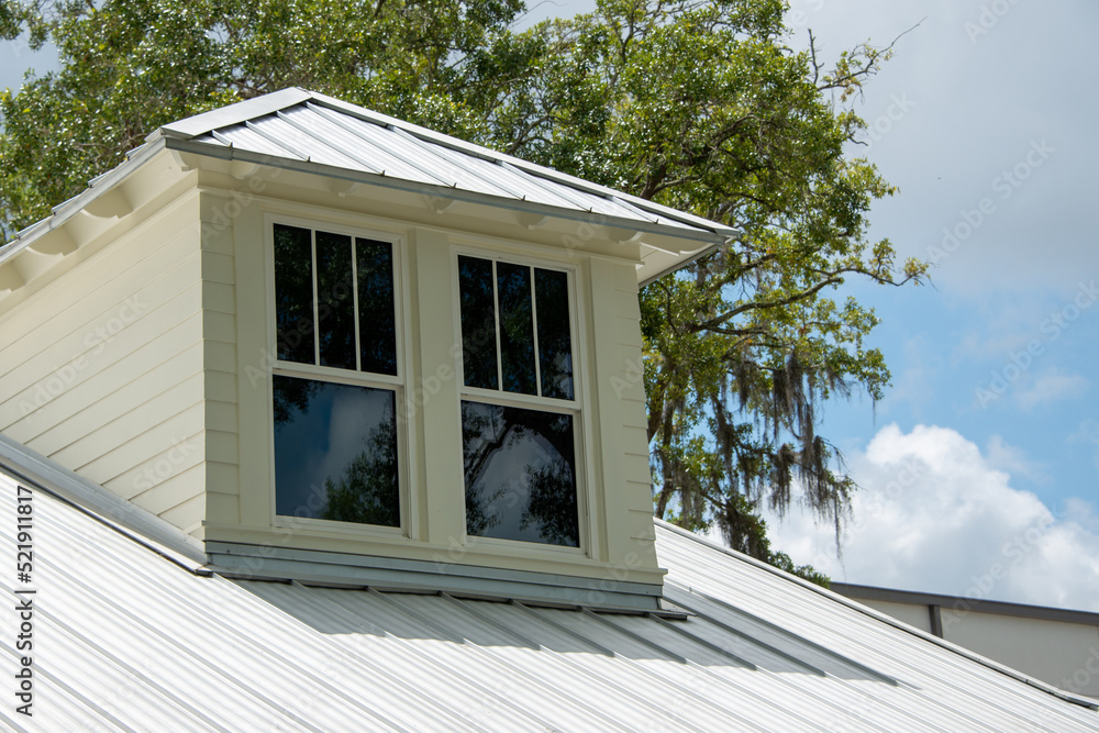 A dormer with multiple double hung windows, a grey metal roof, and pale ...