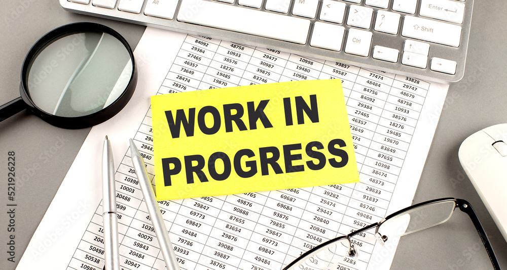 WORK IN PROGRESS text written on a sticky on chart with keyboard and ...