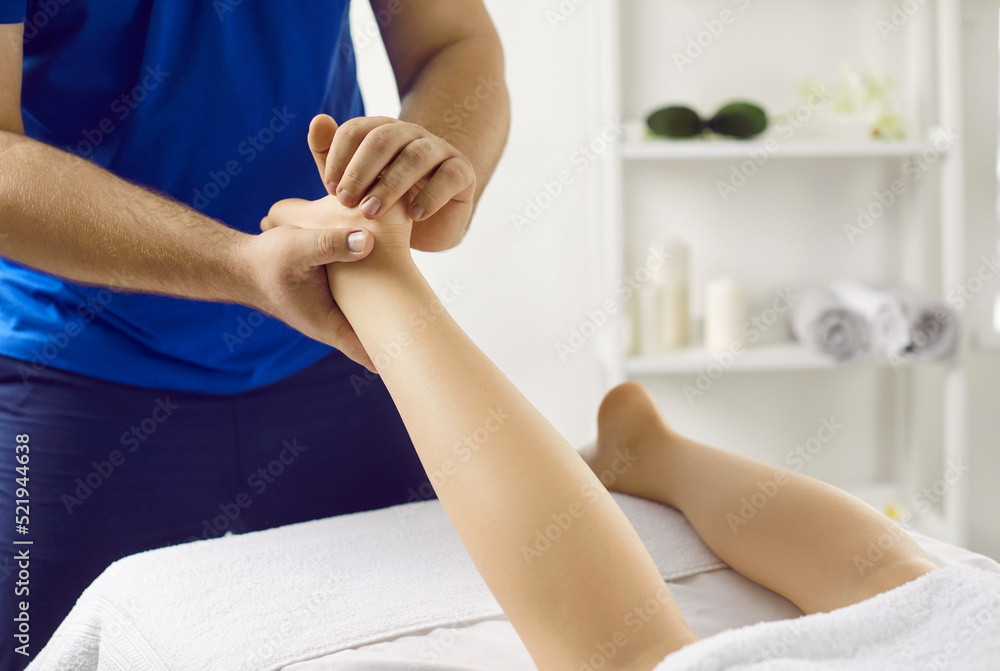 Reflexologist doing remedial therapeutic stress reducing foot massage to female patient ...