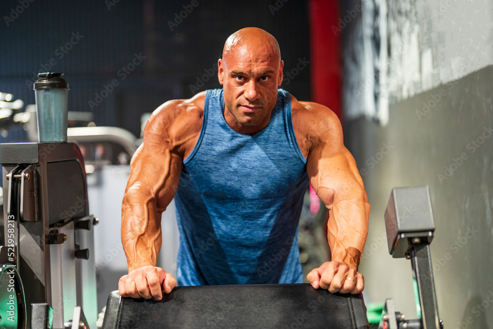 Bald bodybuilder leaning on exercise machine in gym Stock Photo | Adobe ...