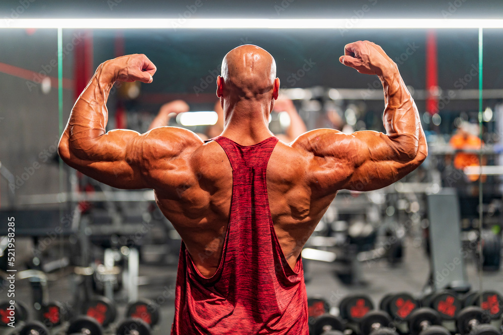 Bodybuilder flexing muscular back standing in gym Stock Photo | Adobe Stock