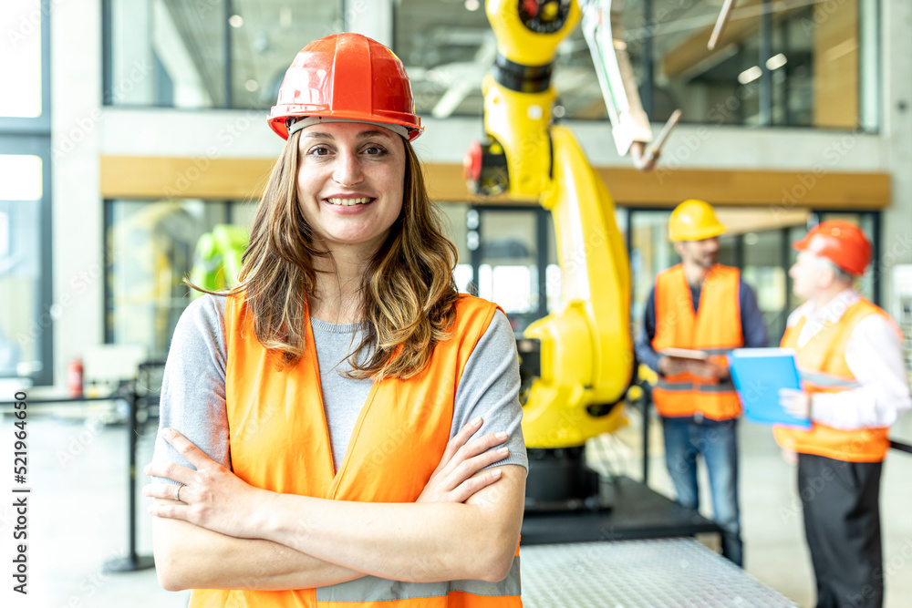 Confident industrial worker standing in robotic factory with arms ...