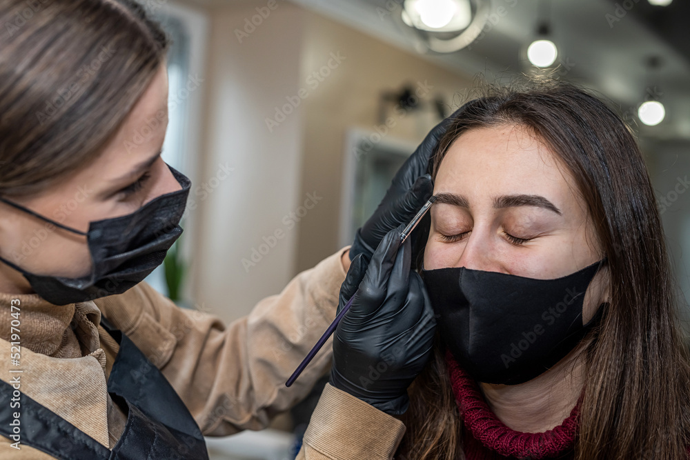 beautiful young client in a special black mask came to the salon for ...