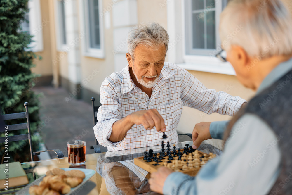 Elderly man plays chess with his friend in backyard of nursing home ...