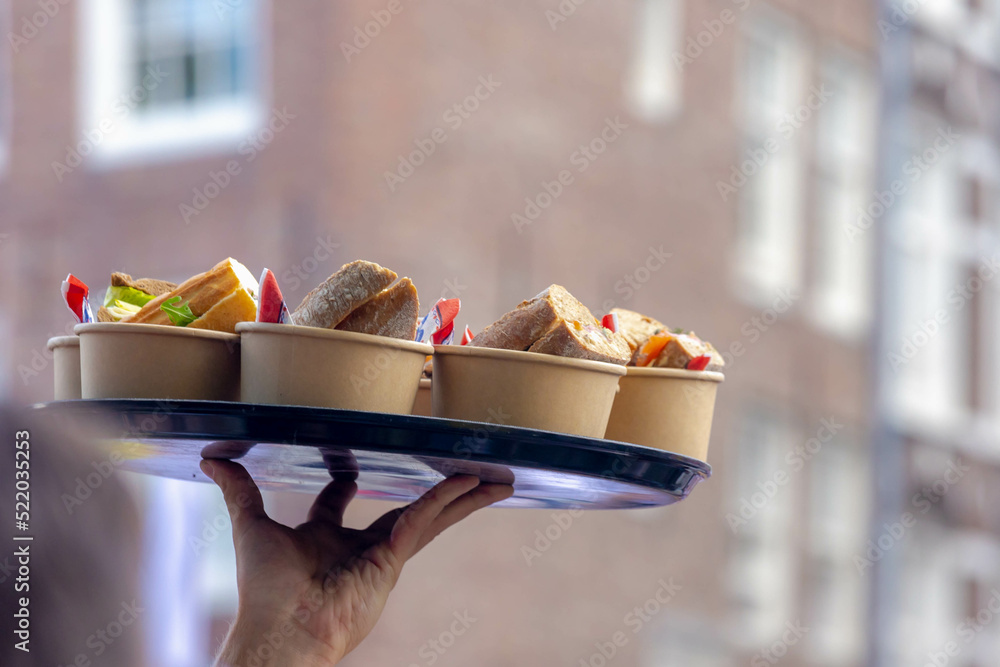 Selective focus of a man hand holding a tray full with sandwiches ...