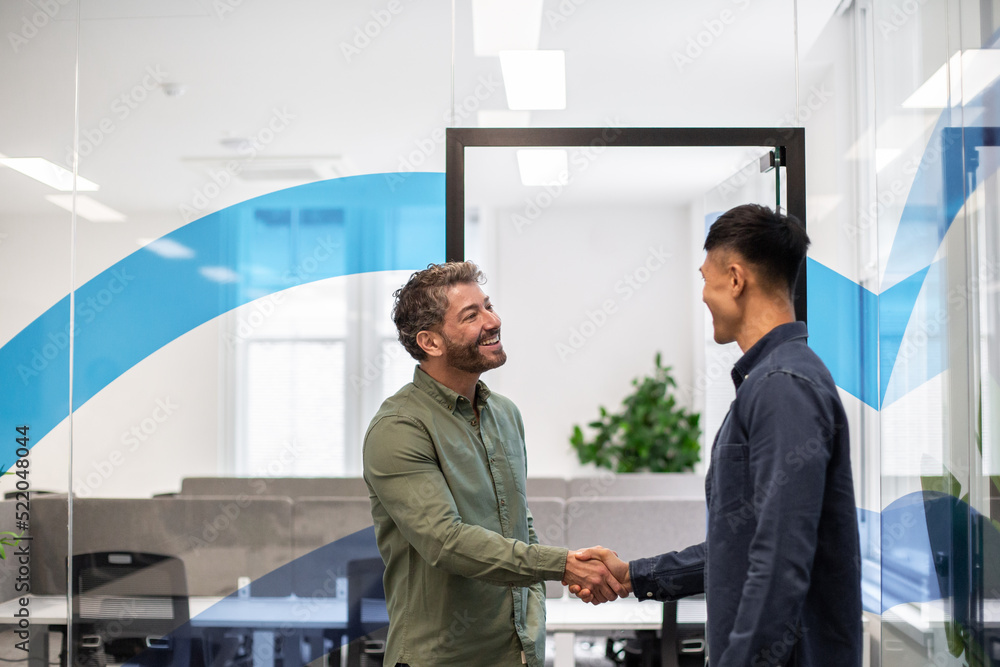 Businessmen shaking hands at a job interview in a corporate office ...