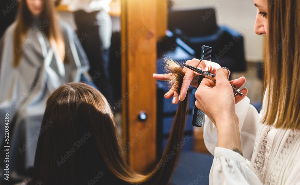 Master woman hairdresser cuts the ends of the girl's hair after washing ...