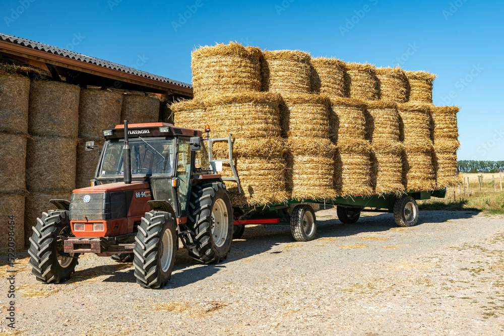 Ballots de paille sur une remorque plateau. Déchargement et stockage à ...