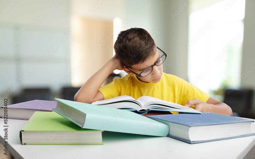 Smiling intelligent schooler teen doing homework, sitting at table ...