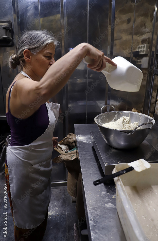 mujer repostera echando harina en cazuela para elaborar pan Stock Photo ...