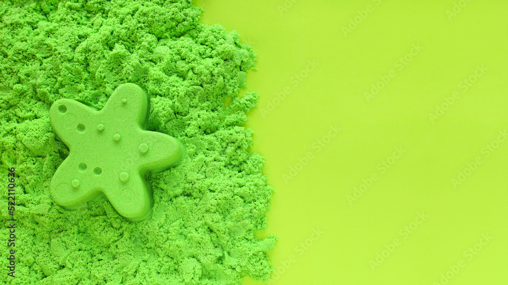 Green kinetic sand with sea-star sand figure on light green paper ...
