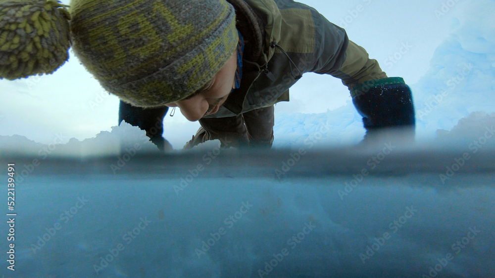 Indigenous Inuit, Inuk, Eskimo hunter at ice fishing hole meniscus ...