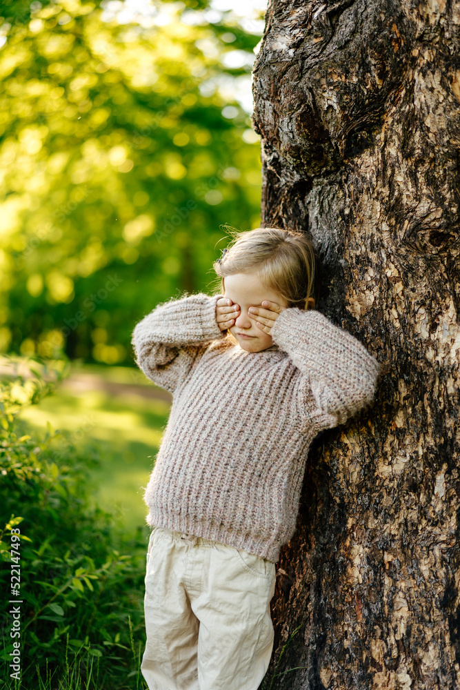Little girl playing hide and seek in countryside Stock Photo | Adobe Stock