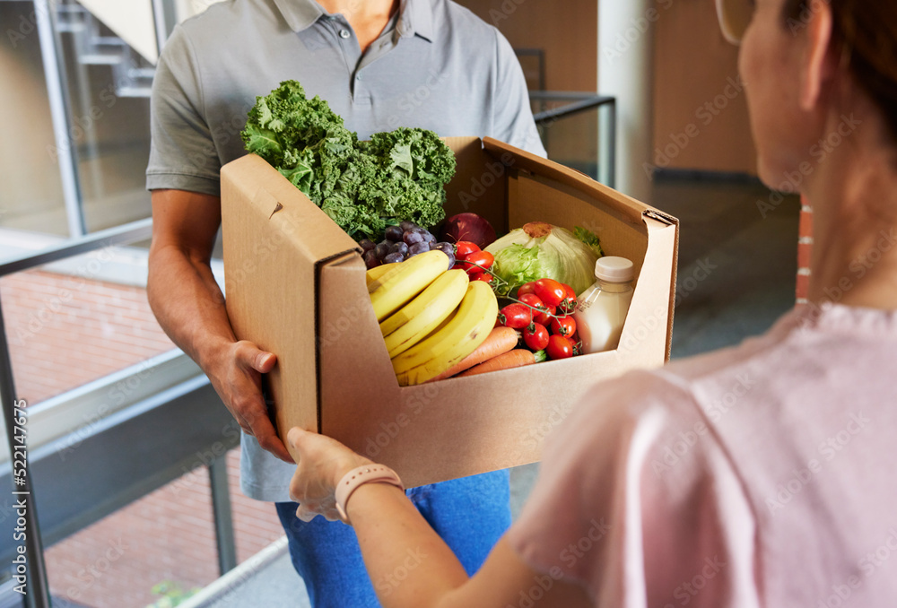 Cropped woman taking fresh groceries from delivery man Stock Photo ...