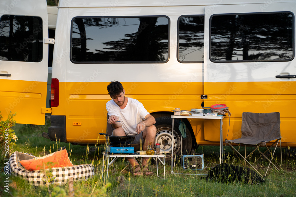 Cooking Man camping with camper van in nature Stock Photo | Adobe Stock
