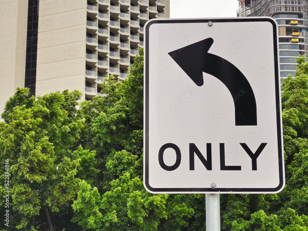 Traffic signal sign to turn left only in lush green trees and city ...