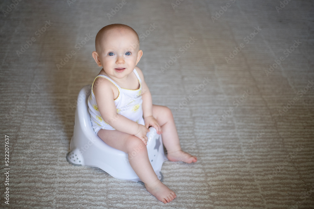 Cute baby in a diaper sitting on a potty. Toilet and potty training. A ...