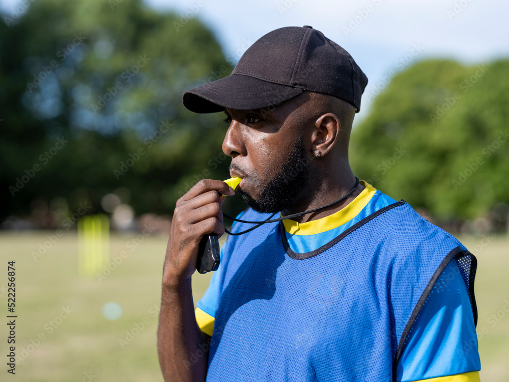 Coach using whistle on soccer field Stock Photo | Adobe Stock