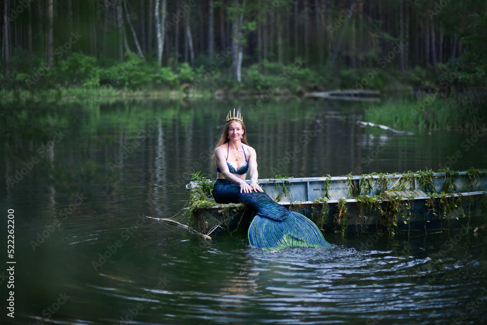 Mermaid story. The little mermaid sits in a boat. Mermaid at sunset ...