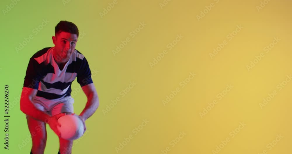Caucasian male rugby player jumping with rugby ball over yellow ...